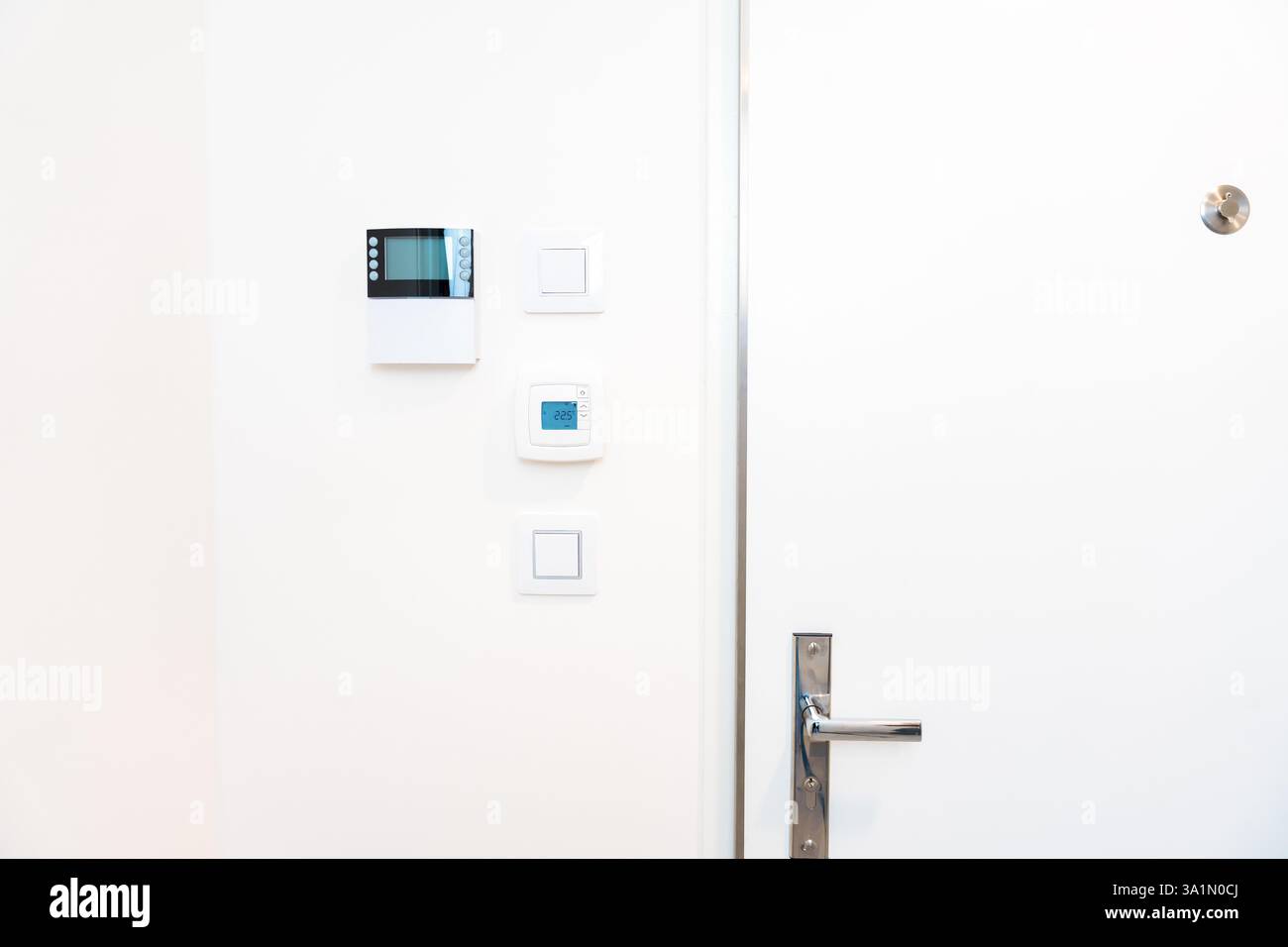 Smart home control panel and thermostat on white wall in modern ...