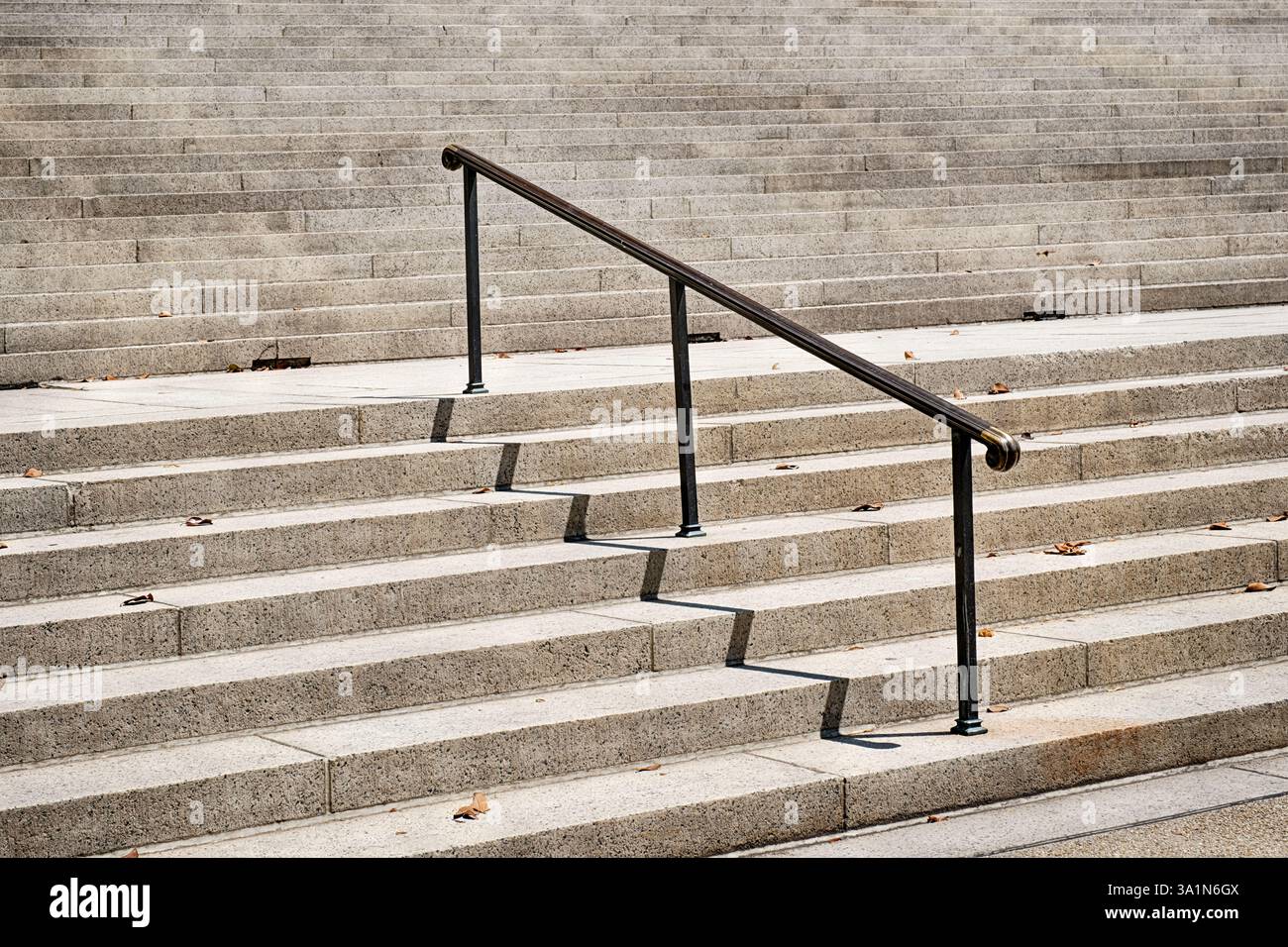 A single metal handrail goes up a portion of the many steps leading up ...