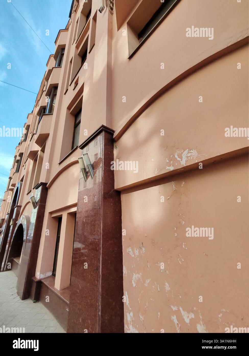 A modern peach building with air conditioning units and round red ...