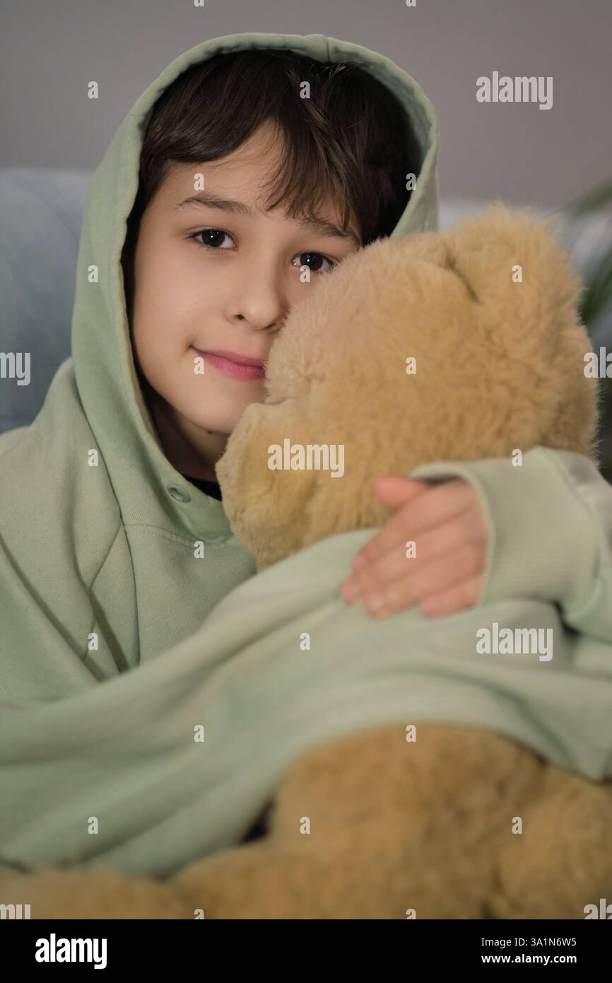 The boy embraces a soft teddy bear, evoking themes of childhood ...