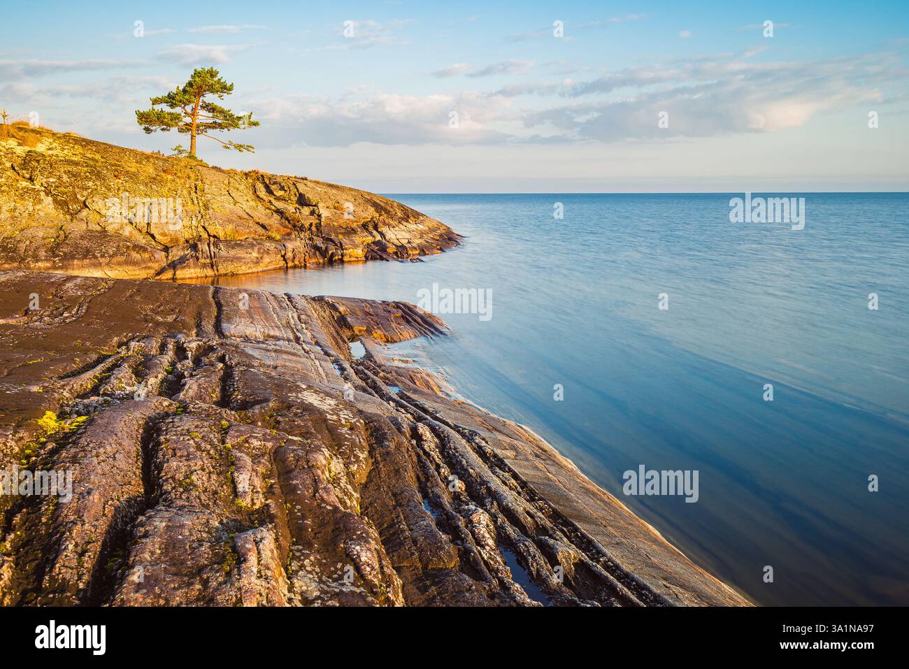 Rocky cliffs meet the tranquil waters of Lake Vanern in Sweden ...