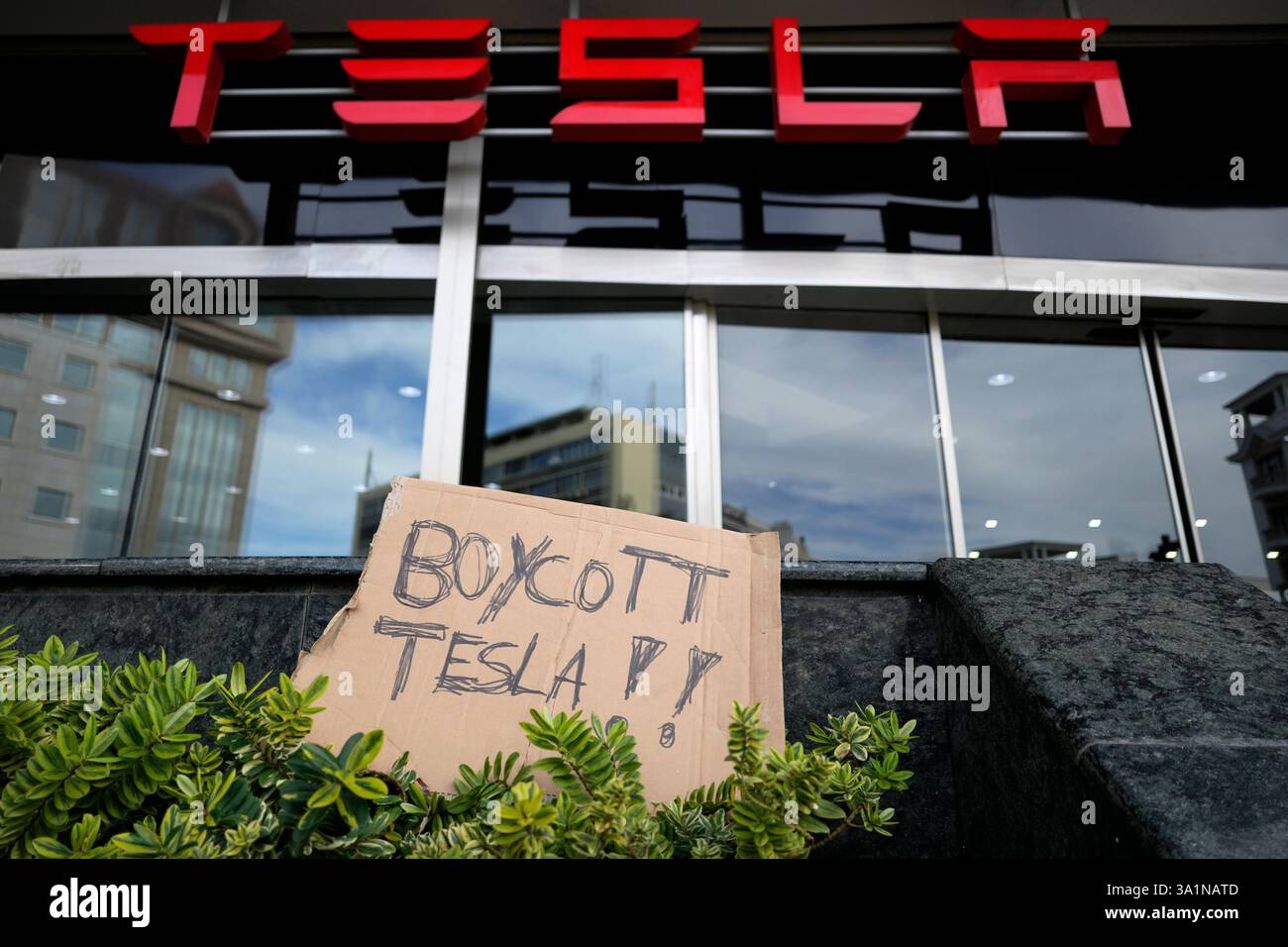 A banner is left outside a Tesla showroom during a demonstration, in ...