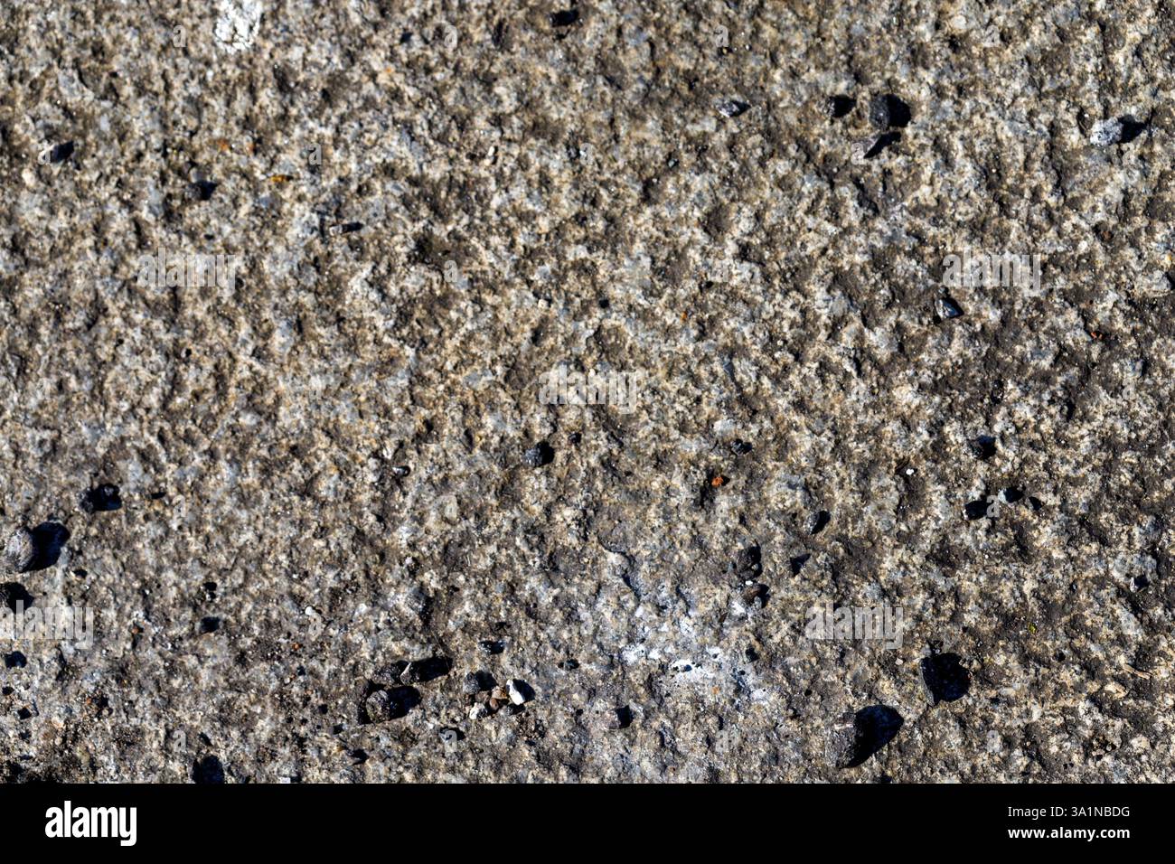 Close-up view of rough gray concrete surface with dark spots and ...