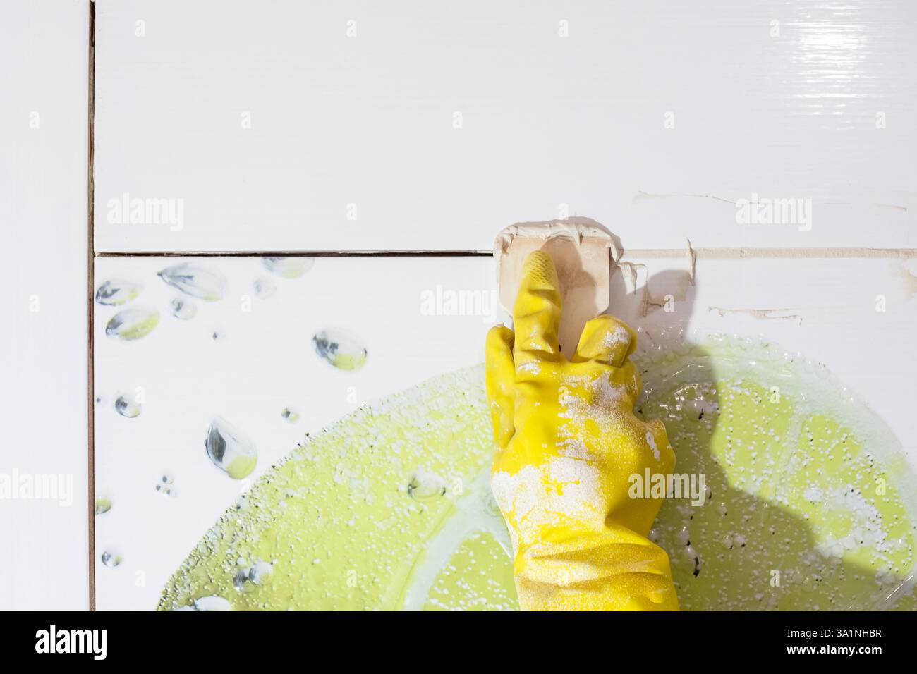 Laying ceramic tiles. The craftsman fills the tile joints with grout ...