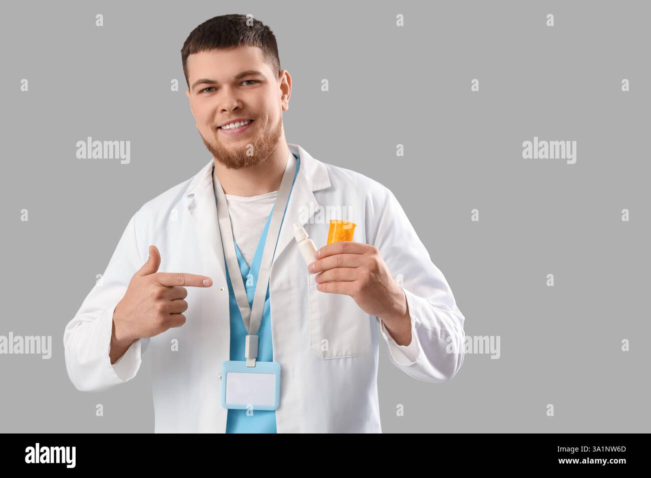 Male ophthalmologist pointing at eye drops and pills on grey background ...