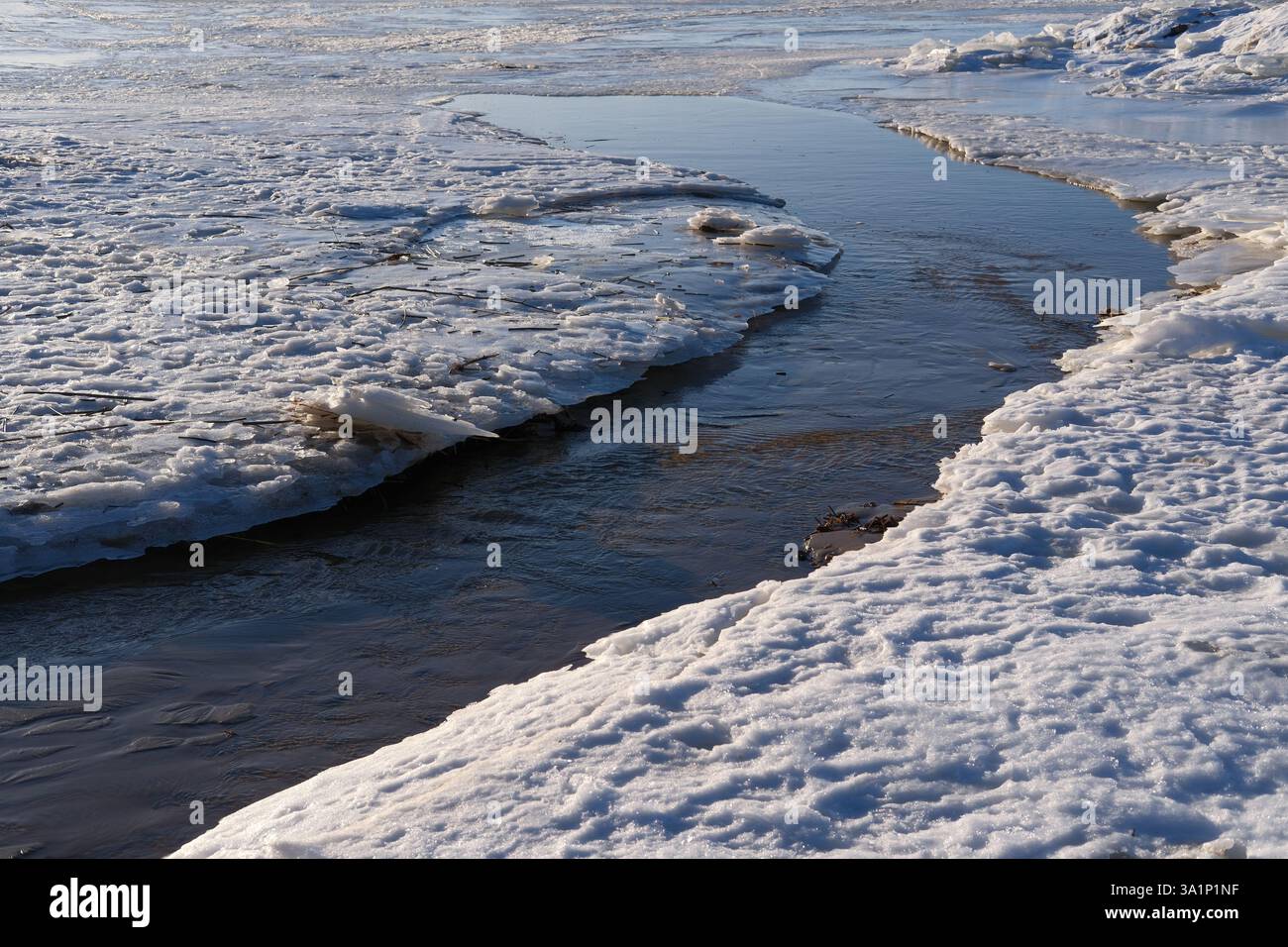 Melting stream running into sea gulf between snowy and icy shores ...