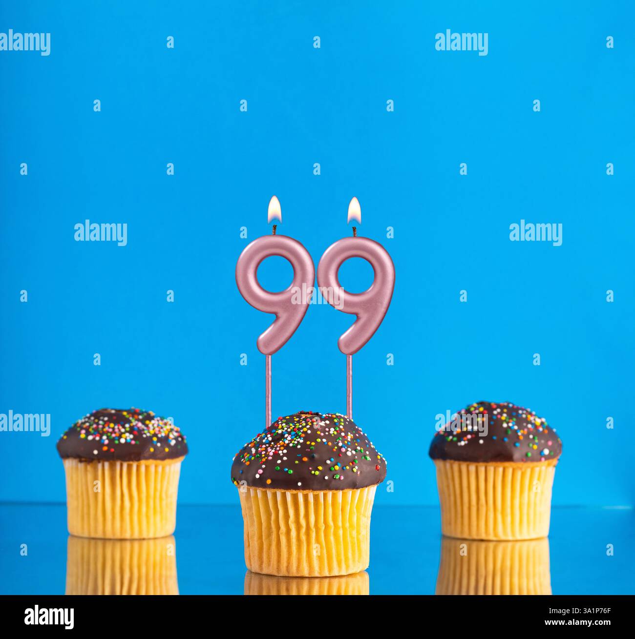 Three birthday cupcakes with number 99 candle - Blue background Stock ...