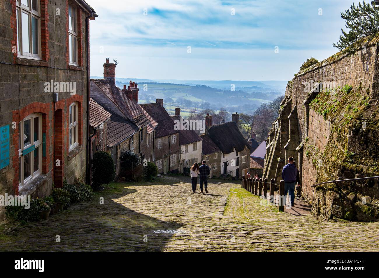 Charming cobblestone street in a historic English village with people ...