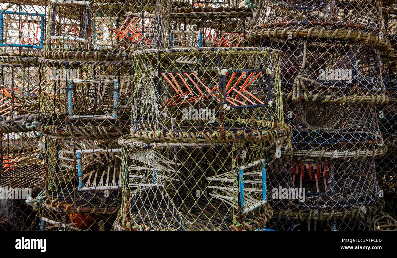 A collection of stacked lobster pots made from metal and rope, used for ...