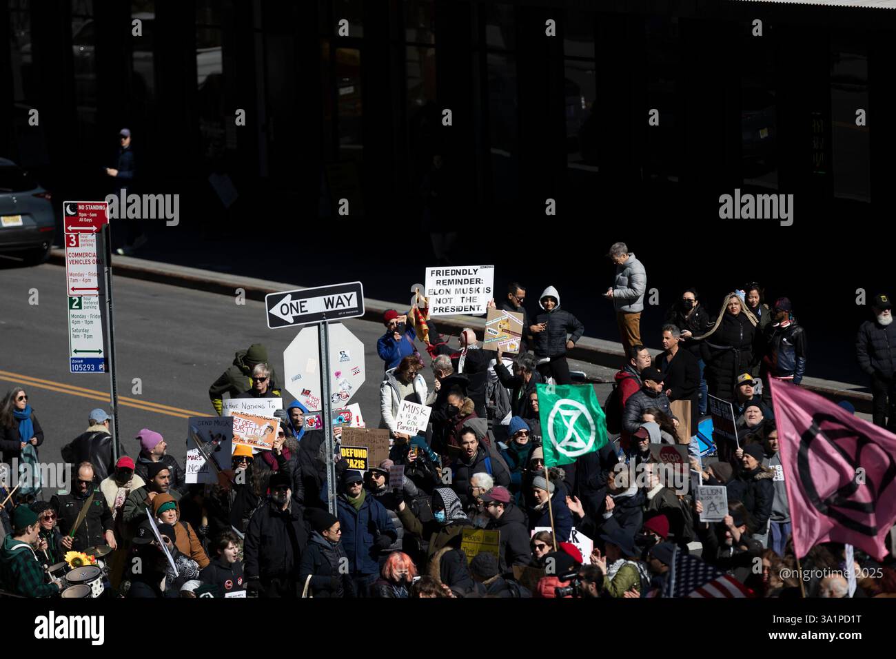 A protestor outside a Tesla showroom in Manhattan holds a sign that ...