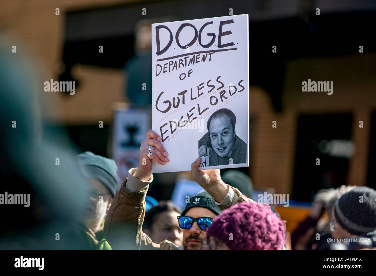 A protestor outside a Tesla showroom in Manhattan holds a sign that ...