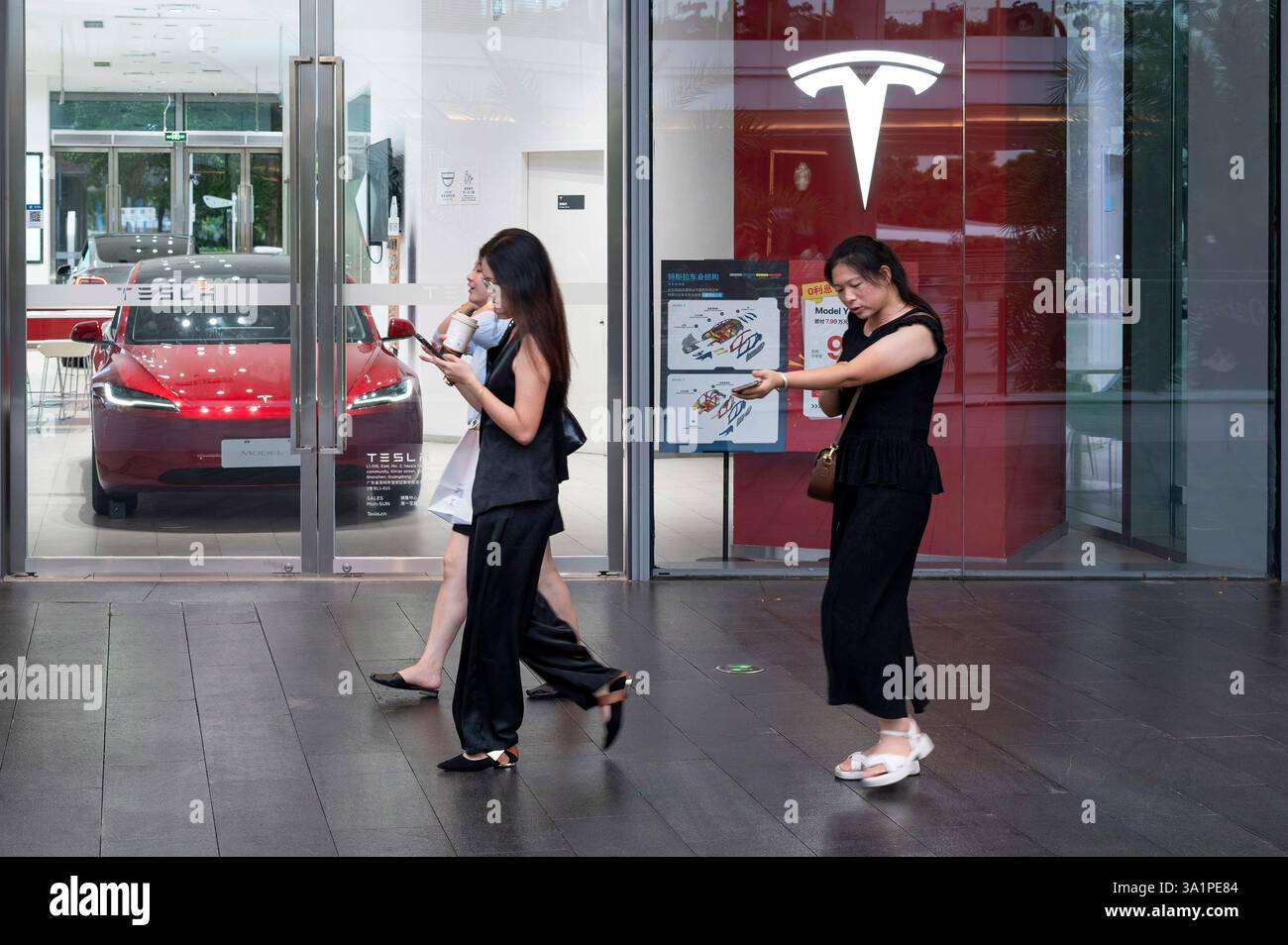 Pedestrians walk past the American electric company car Tesla Motors ...