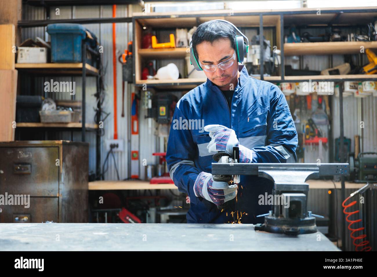 Latin worker wearing safety glasses and ear protection while using an ...