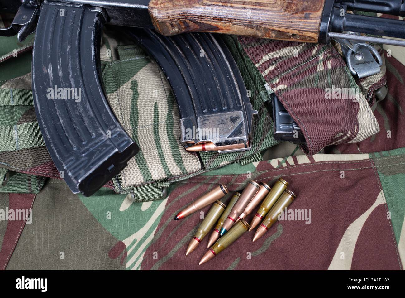 AK assault rifle with cartridges on camo uniform background Stock Photo ...