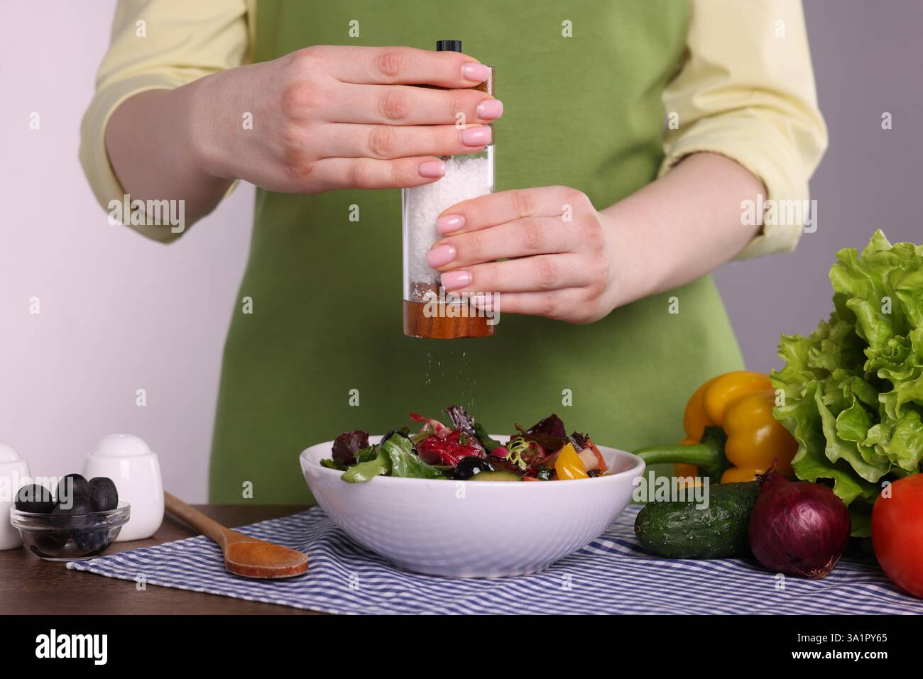 Woman salting tasty salad at wooden table against white background ...
