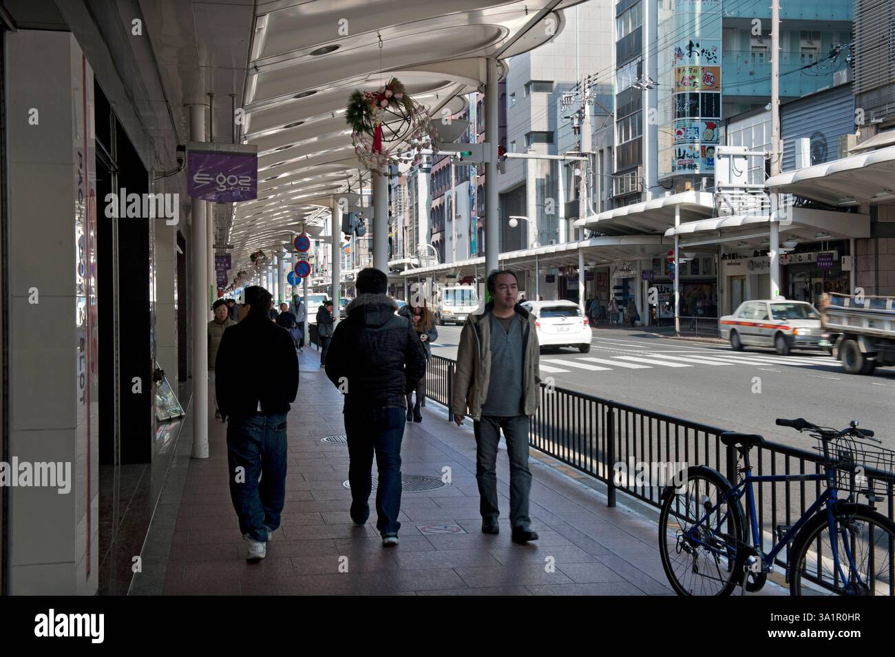 People walking along the covered sidewalk of Shijo-dori, the main ...
