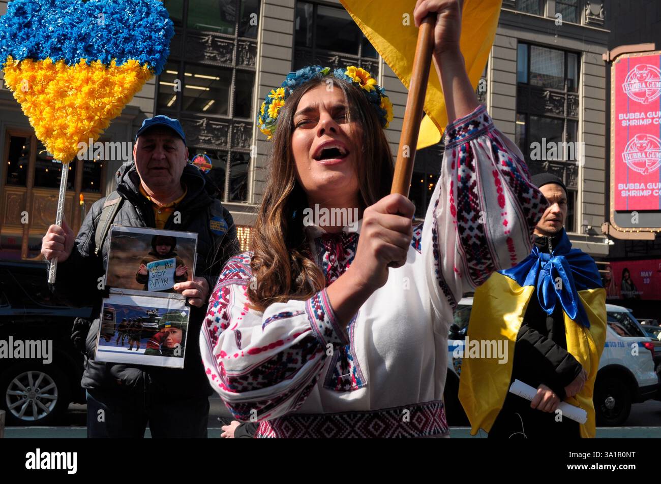 A pro-Ukraine demonstrator wears a flower wreath and holds the ...