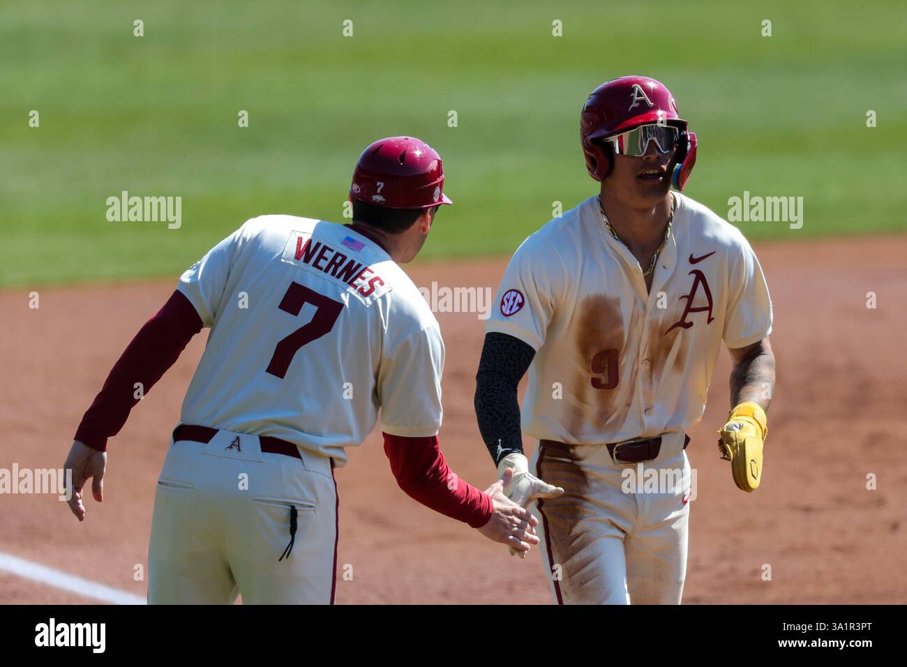 March 9, 2025: Arkansas third base coach Bobby Wernes reaches to tap ...