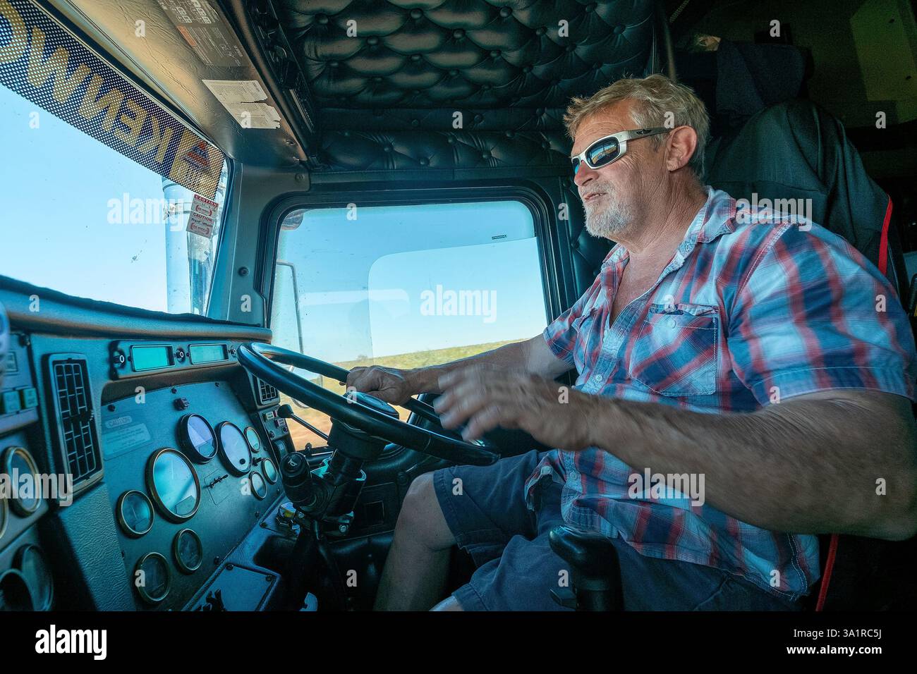 A long haul truck driver driving his Kenworth truck on the outback ...