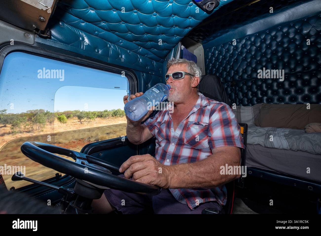 A long haul truck driver driving his Kenworth truck on the outback ...