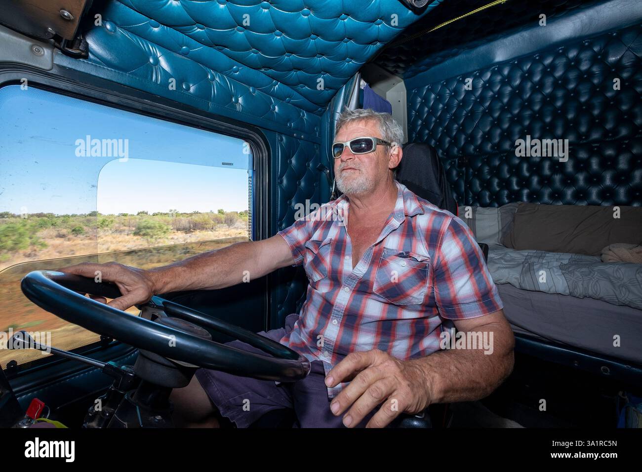 A long haul truck driver driving his Kenworth truck on the outback ...