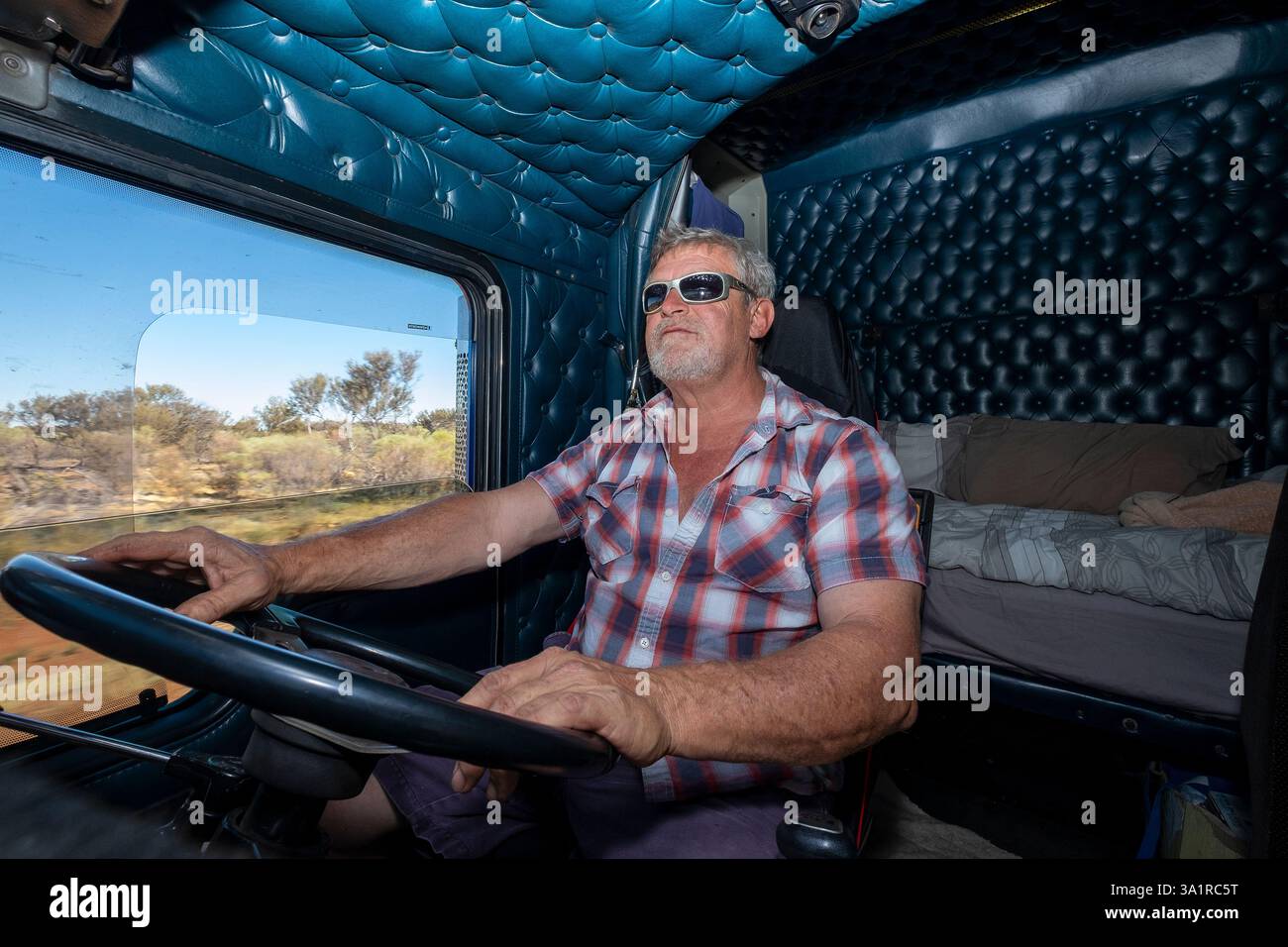 A long haul truck driver driving his Kenworth truck on the outback ...