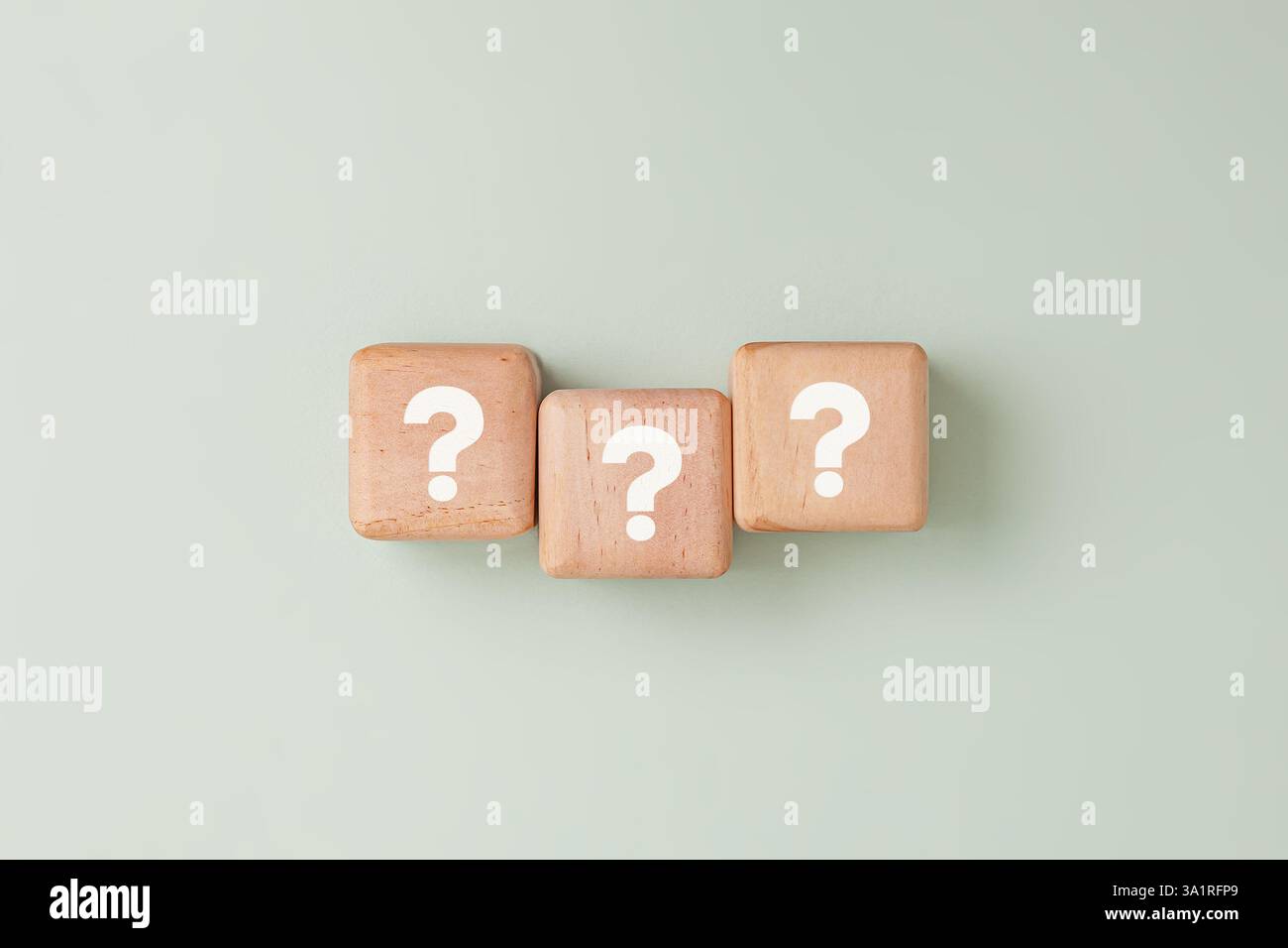 Three wooden blocks with white question marks in straight line against ...