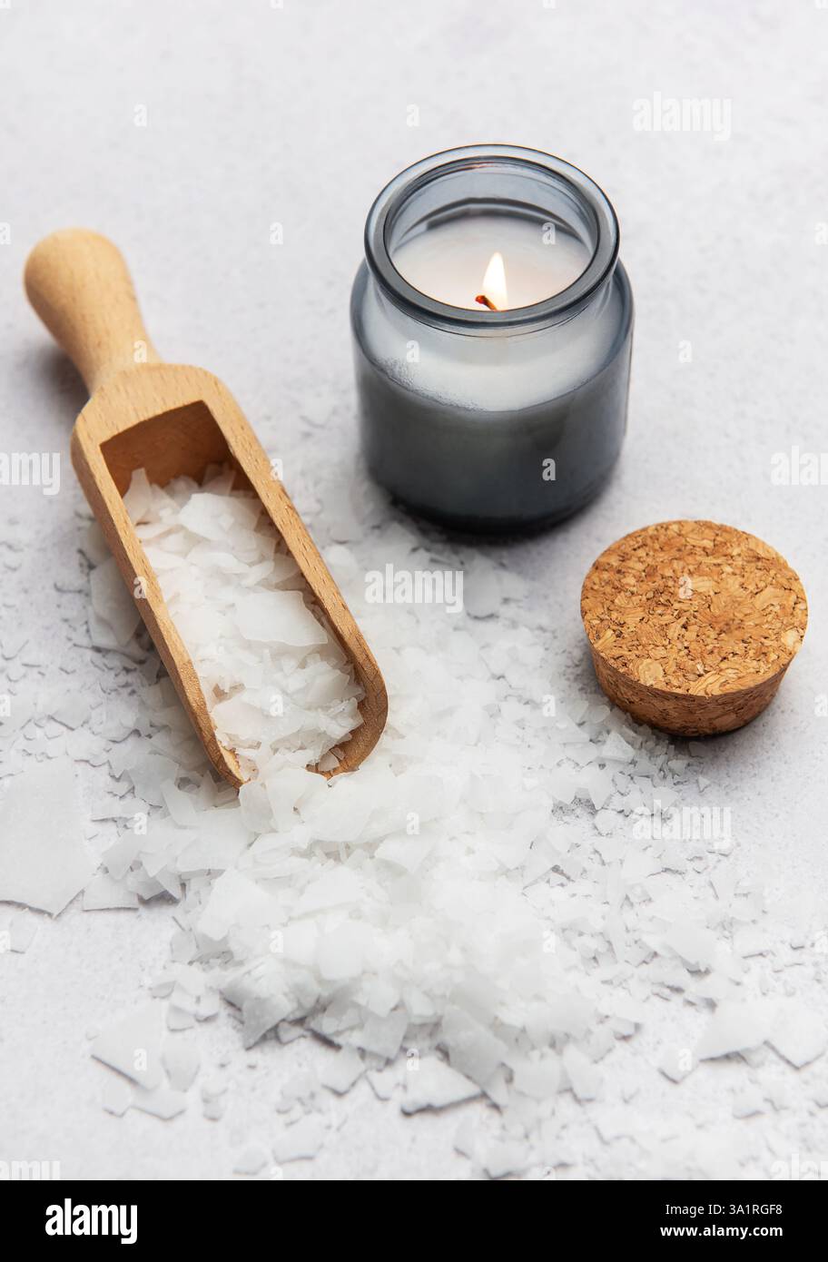 Magnesium bath flakes in wooden scoop with burning candle for relaxing ...