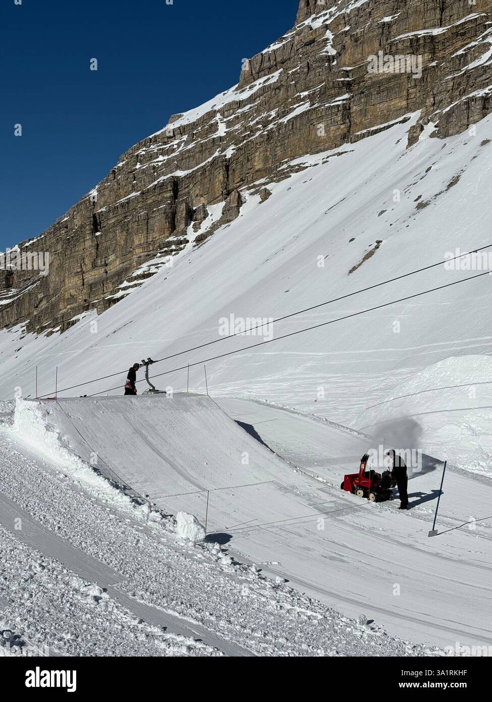 Ski resort snow grooming with cable car and workers preparing a ...