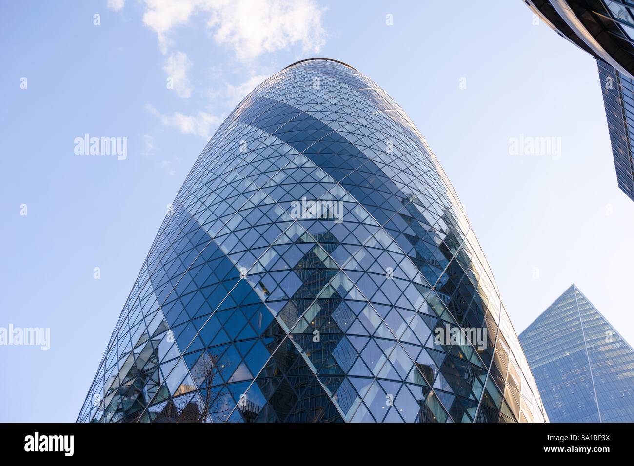 The Gherkin rises prominently against a clear blue sky, showcasing its ...