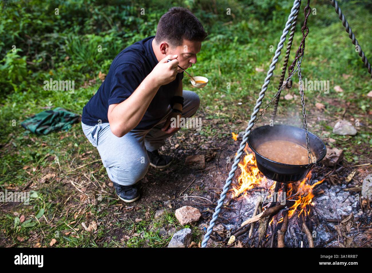 Hiker tasting a hot soup cooked on a bonfire in the woods Stock Photo ...