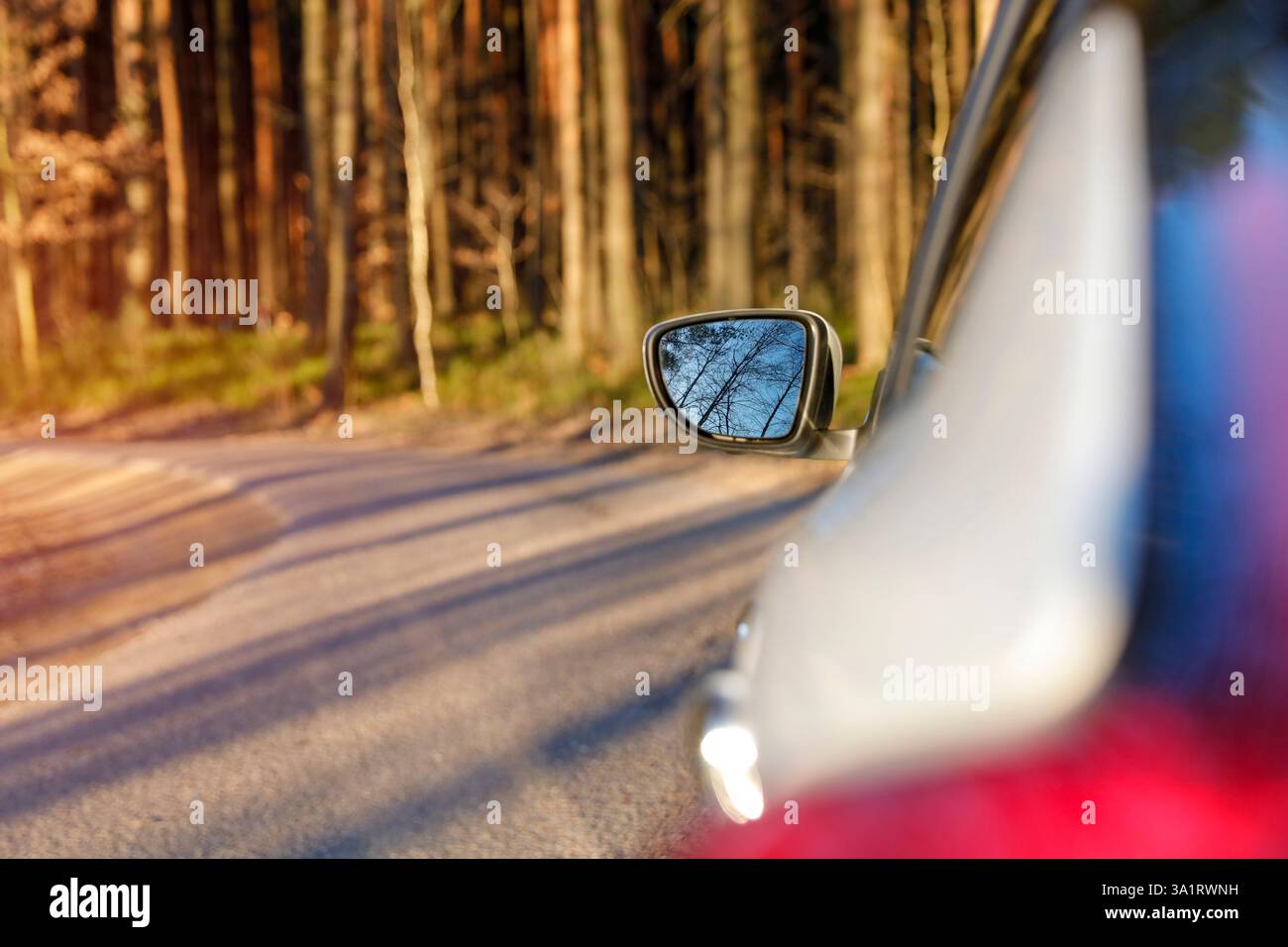 White car parked on the side of paved road that winds through forest ...