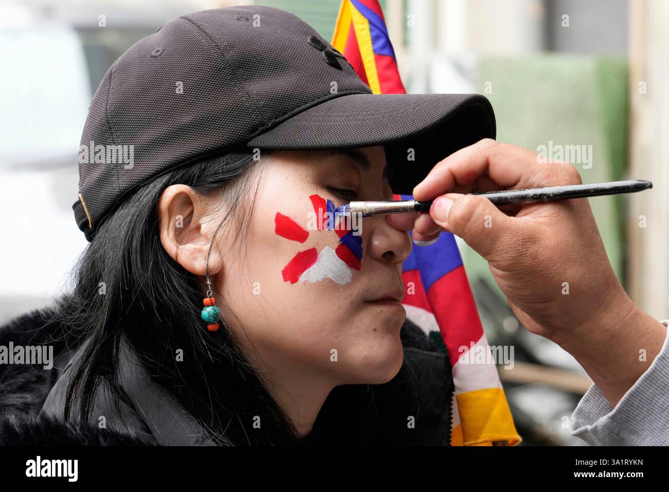 An exiled Tibetan gets her face painted in the colors of the Tibetan ...