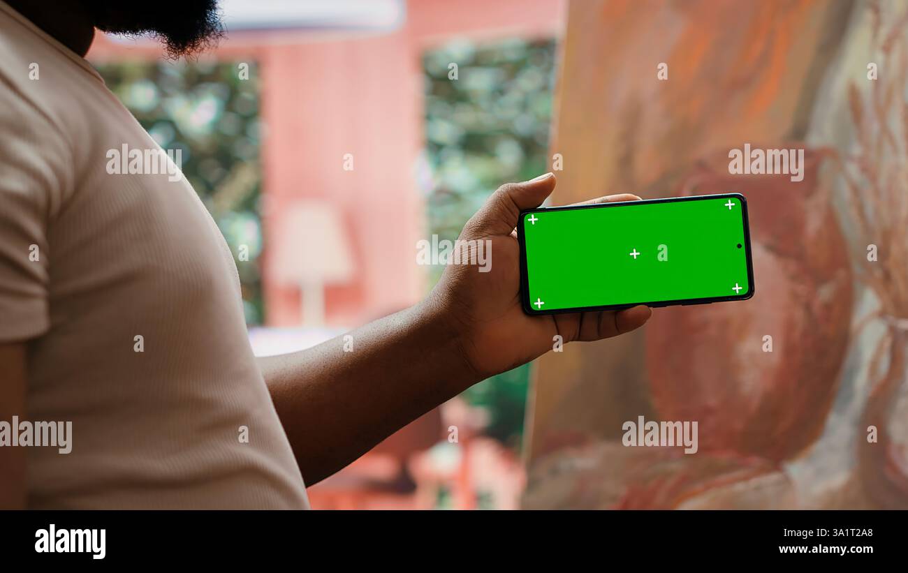 Young artist looking at isolated chroma key display in painting atelier ...