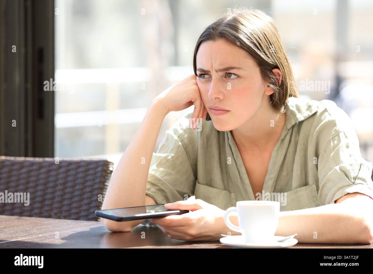 Angry woman complaining in a bar holding phone and thinking looking ...