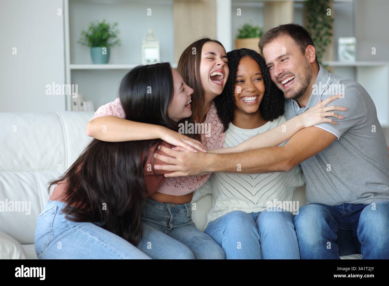 Four diverse happy friends hugging sitting on a sofa at home Stock ...