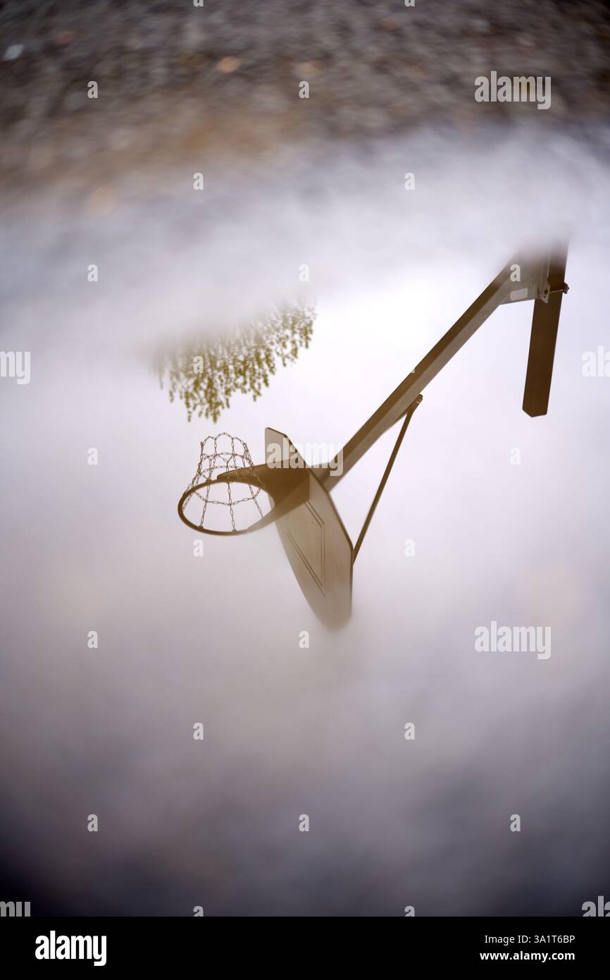Basketball hoop reflecting in puddle after rain shower Stock Photo - Alamy