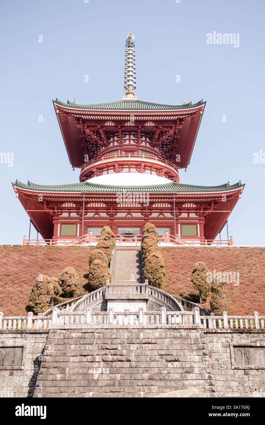A majestic red pagoda stands tall against a clear blue sky in Japan ...