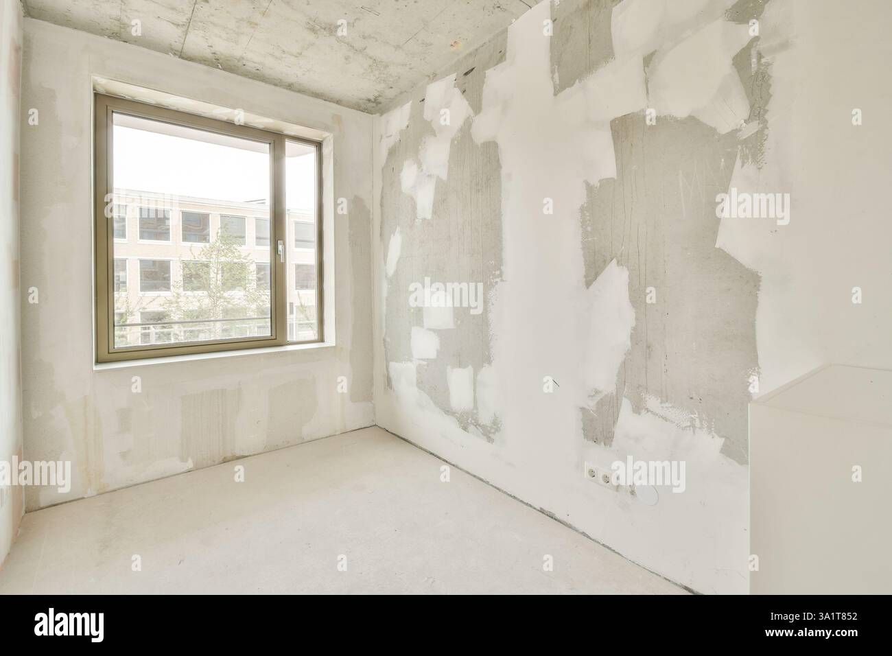 A vacant room with plastered walls and a large window revealing an ...