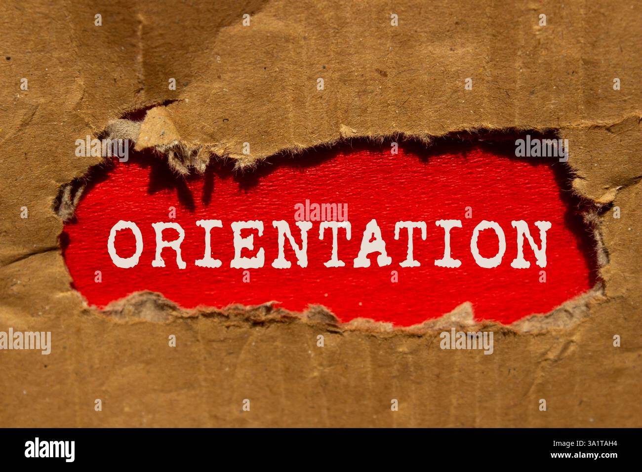 Orientation message written on ripped torn cardboard paper on red ...