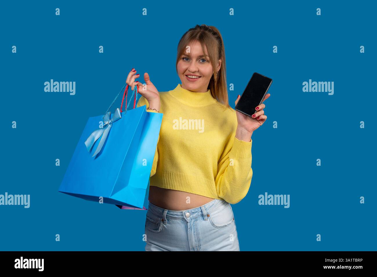 Happy customer showing smartphone screen and holding shopping bag after ...
