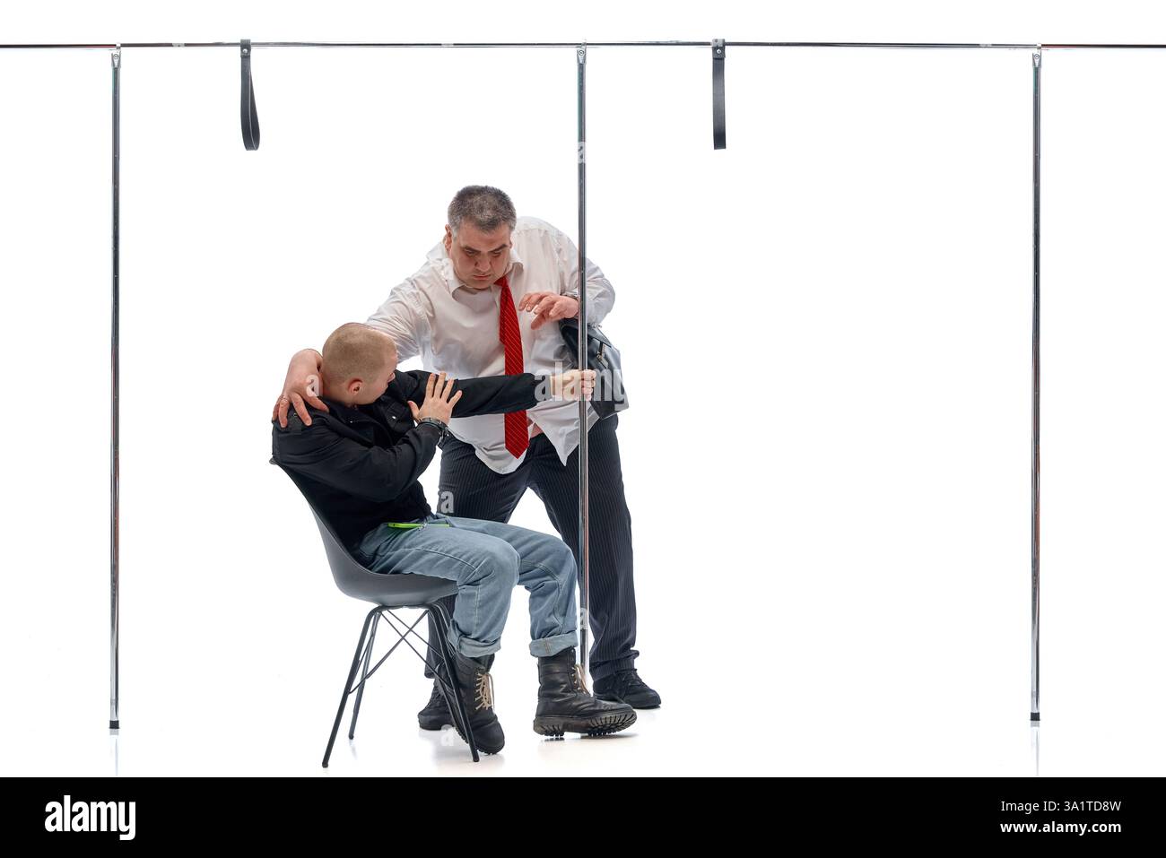 Older man gripping younger man's arm in heated exchange against white ...