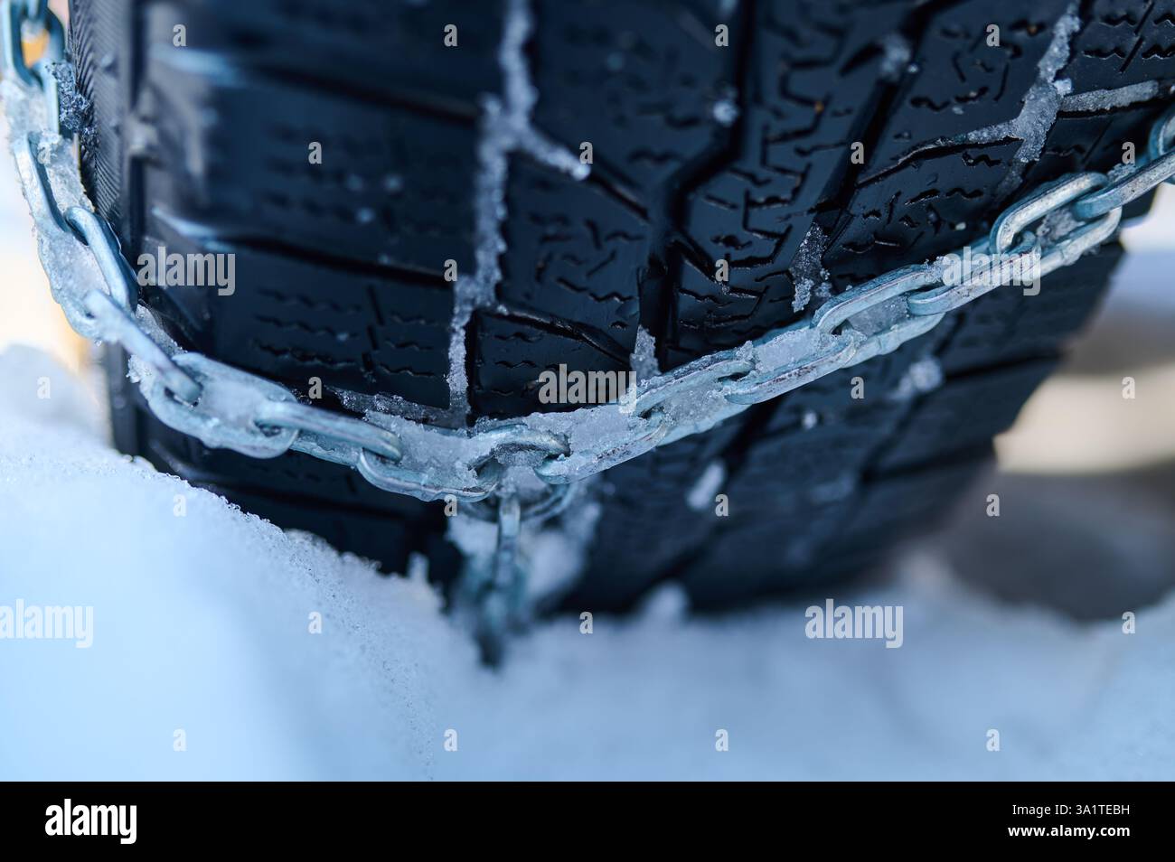 Close-up of a winter tire with snow chains covered in ice and snow ...
