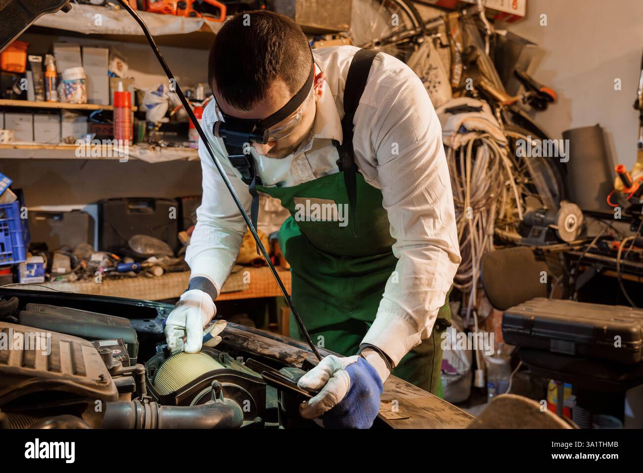 Focused Mechanic Wearing Headlamp and Gloves Repairing Car Engine in ...