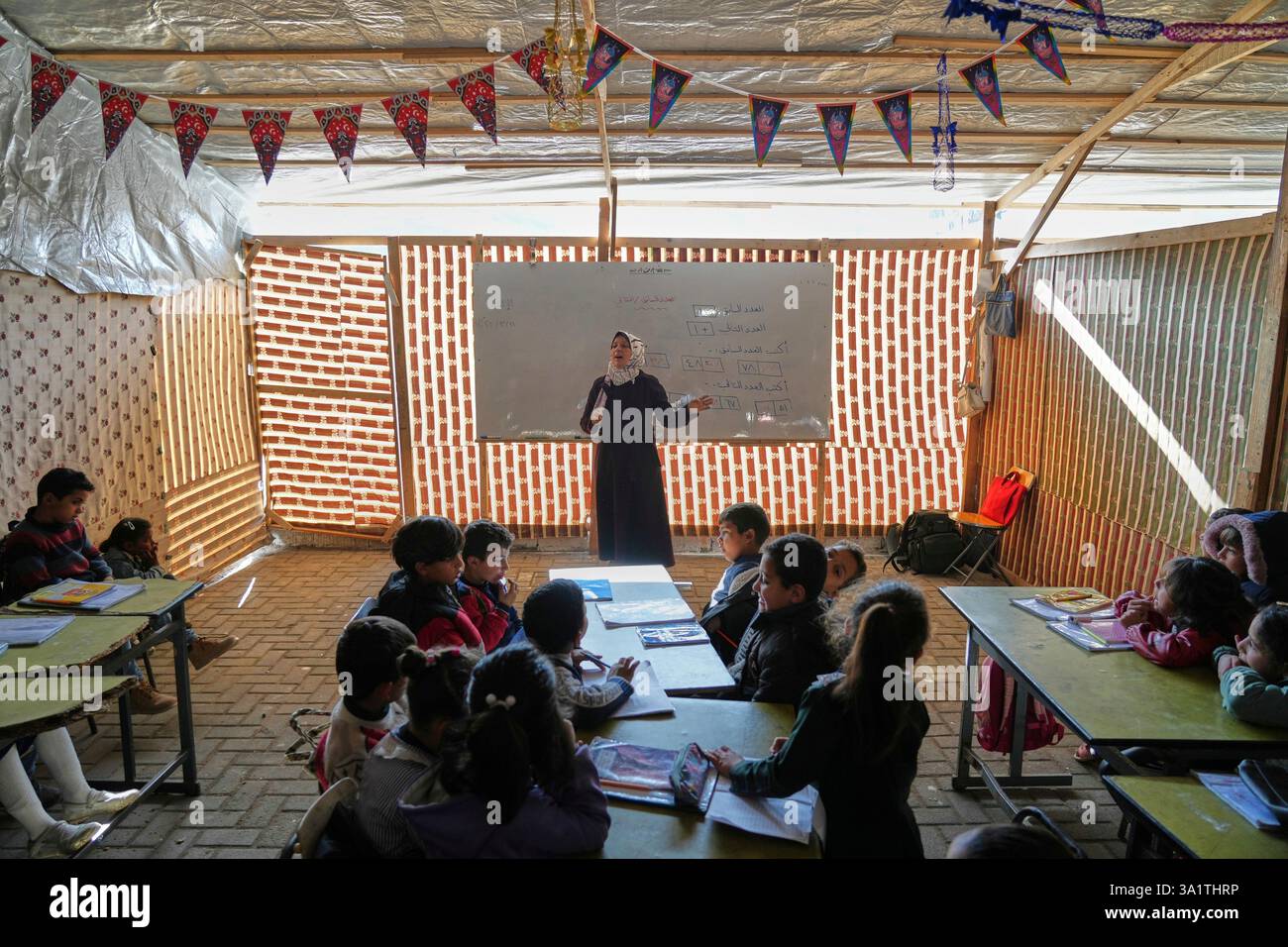 Palestinian children take a lesson in a makeshift classroom located ...