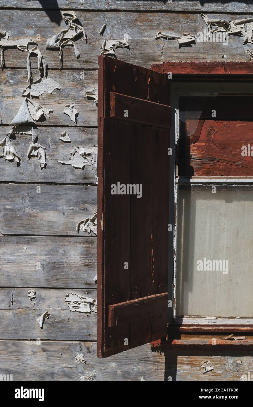close-up of an old wooden window with a partially open red shutter on a ...