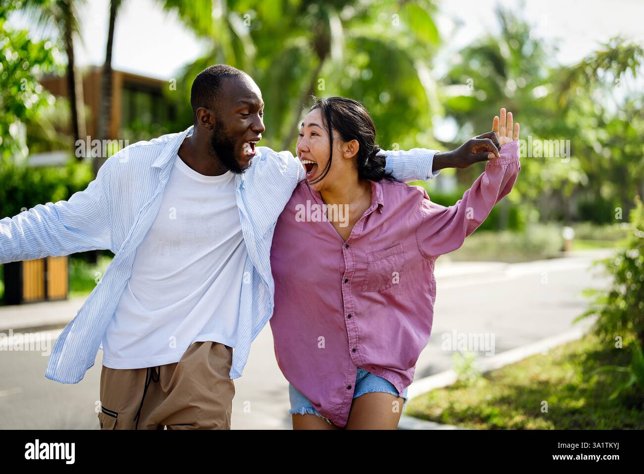 Happy interracial couple laughing together outdoors, enjoying a ...