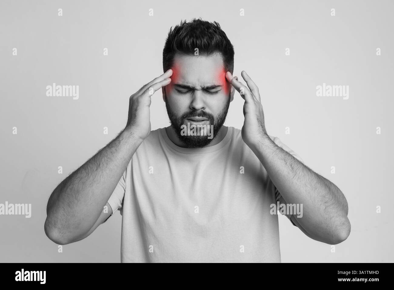 Young man suffering from headache on light background. Black and white ...