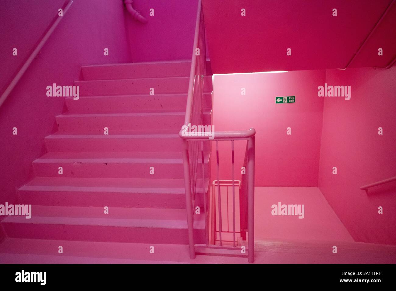 Pink stairs in building with fire escape sign Stock Photo - Alamy