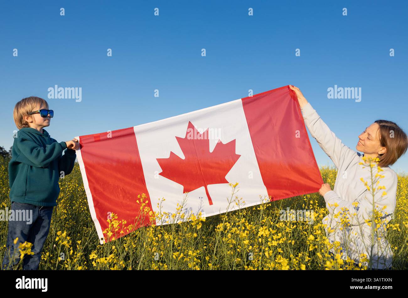 woman and child, mother and son, holding a large Canadian flag standing ...